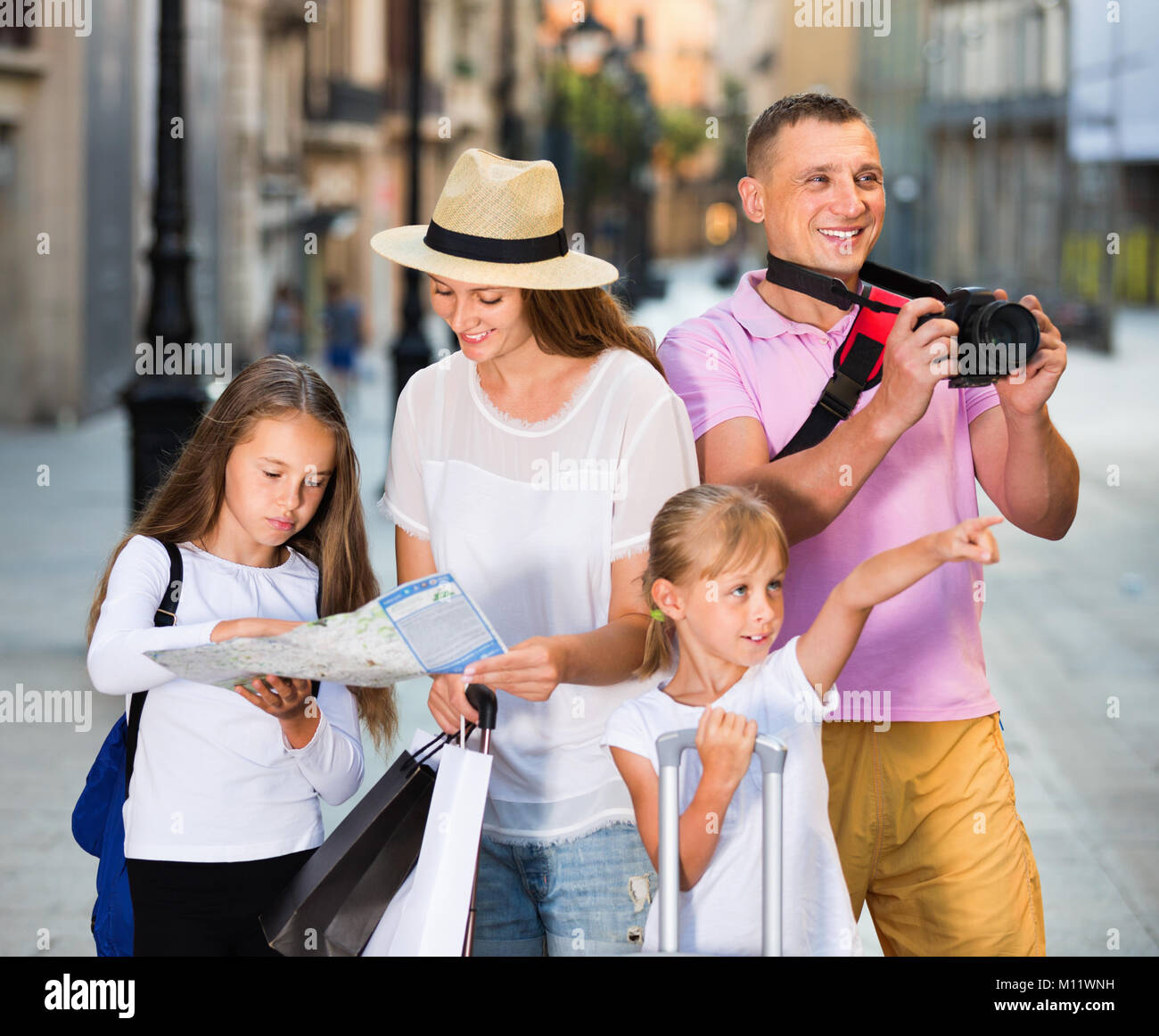 Happy cheerful tourist family using map and taking photo of city while ...
