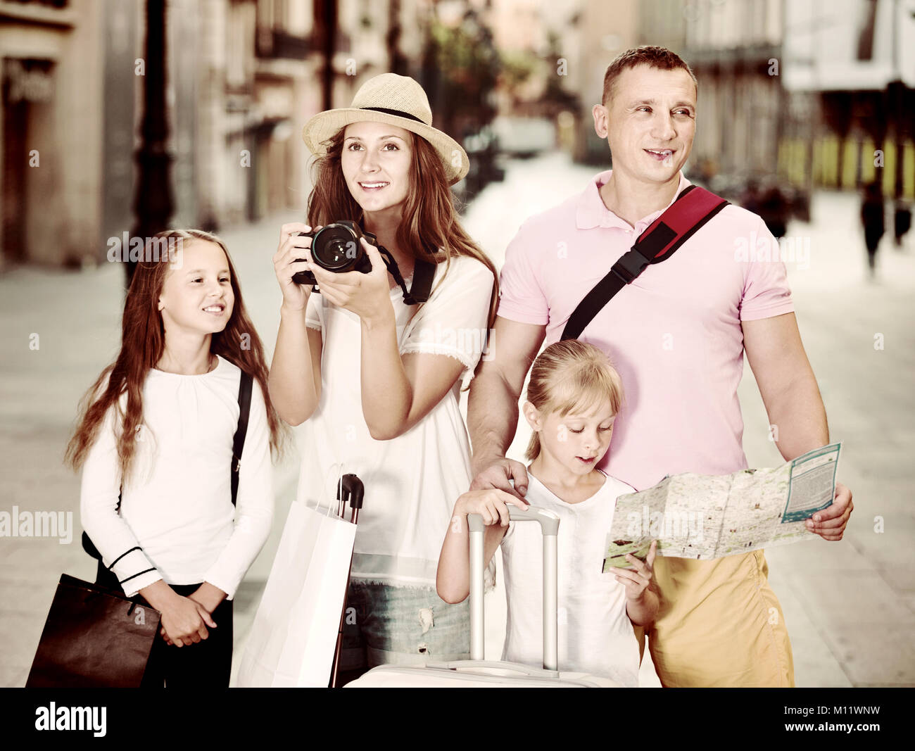 Happy tourist family using map and taking photo of city while strolling ...