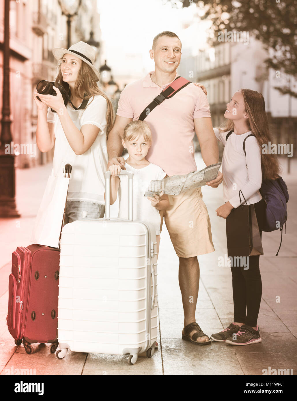 Positive tourist family with kids using map and making amateur photo of ...