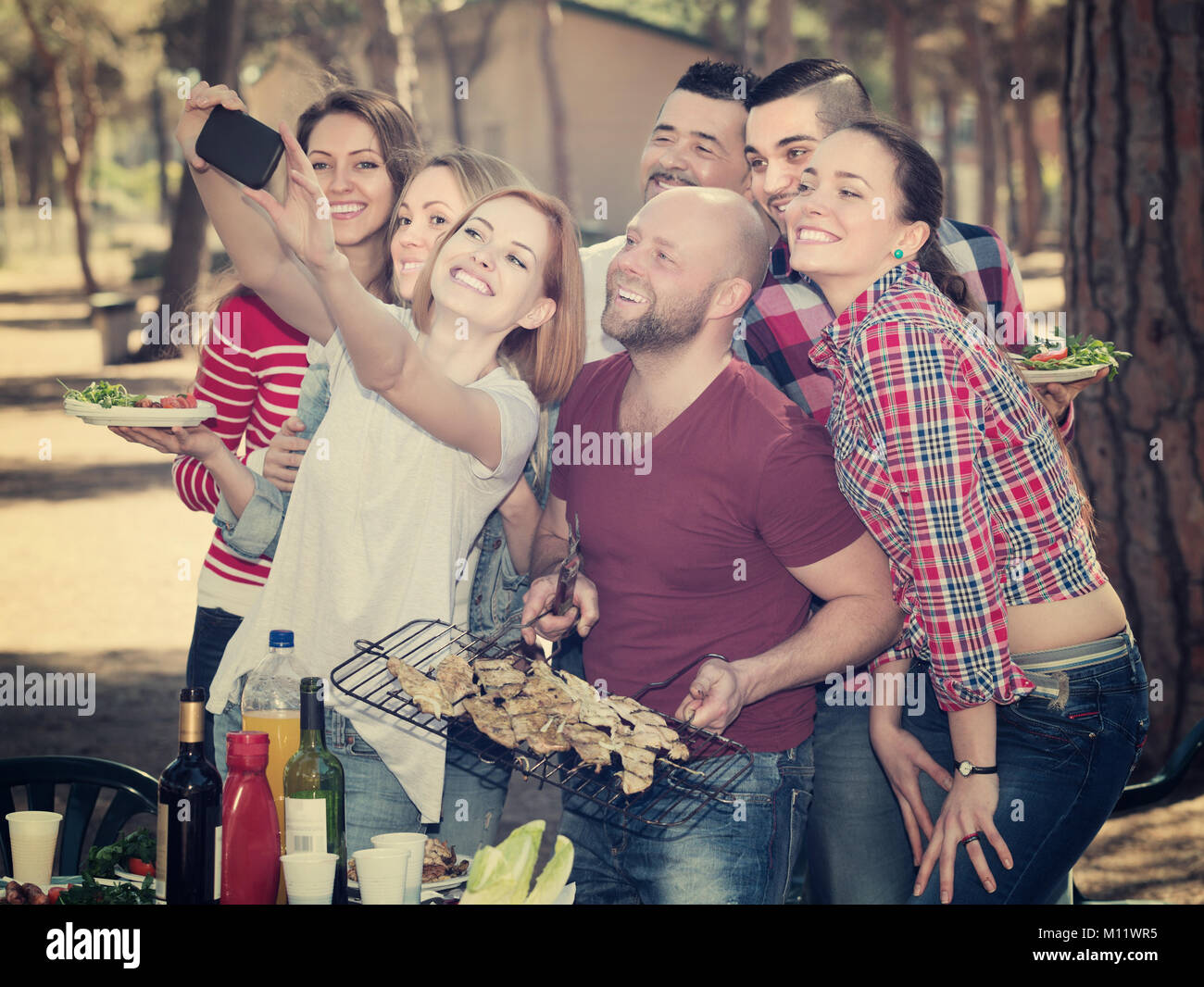 Positive young colleagues making mutual photo at summer grill party ...