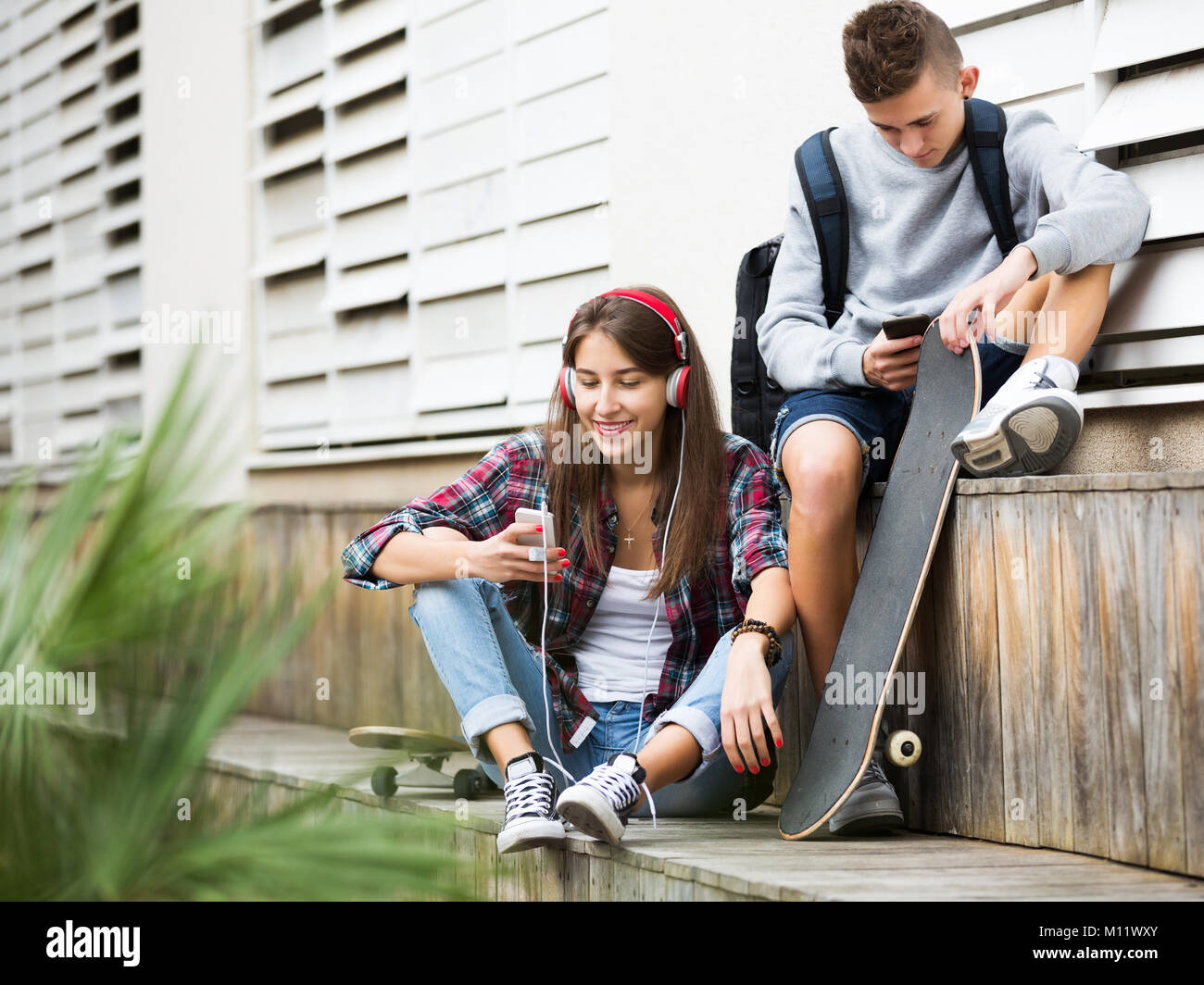 Happy friends relaxing with mobile phones in sunny day outdoors Stock ...