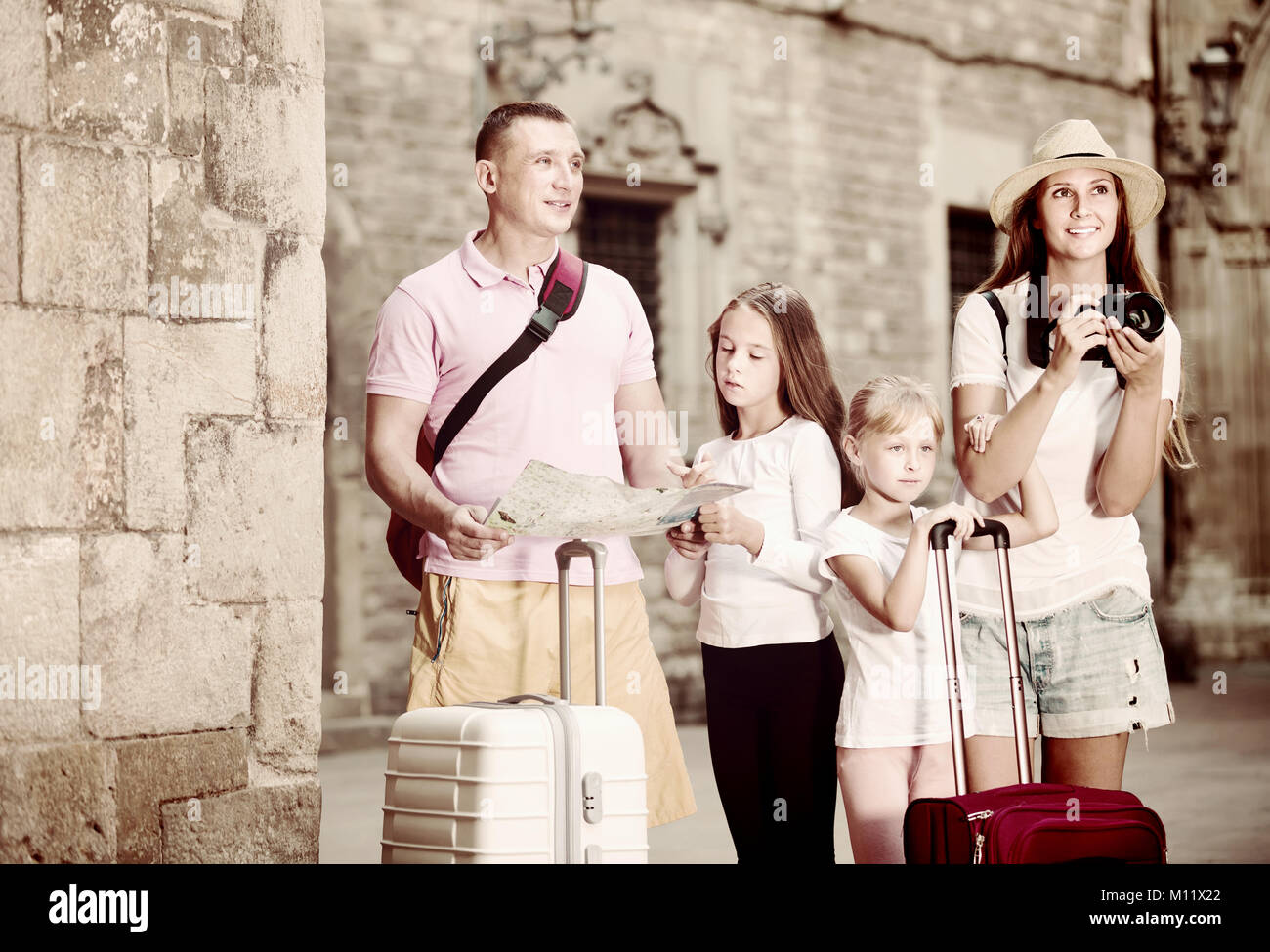 Portrait of young parents tourists with kids using map and making photo ...