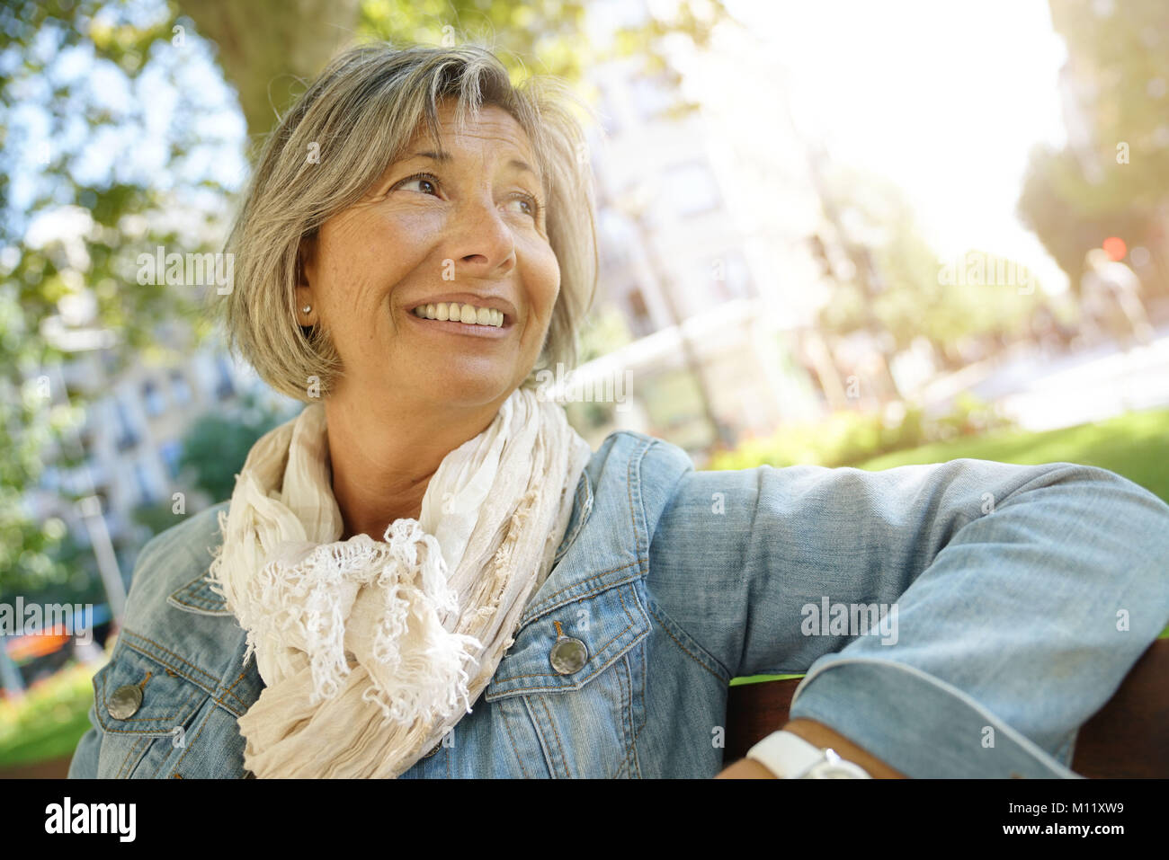 Portrait of smiling senior woman sitting on bench Stock Photo - Alamy