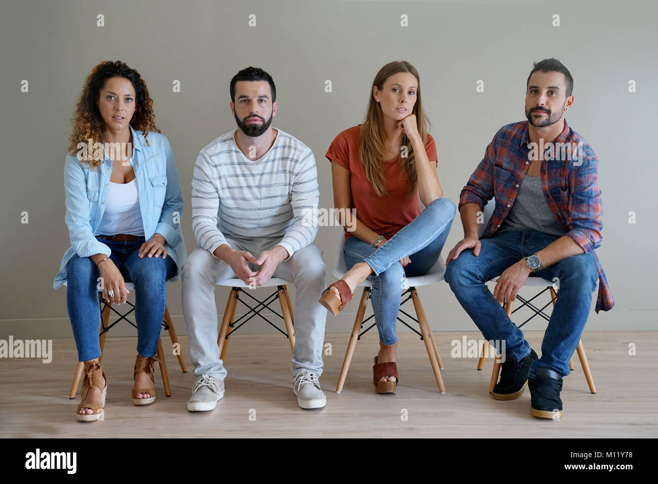 Group of young people sitting on chairs, isolated Stock Photo - Alamy