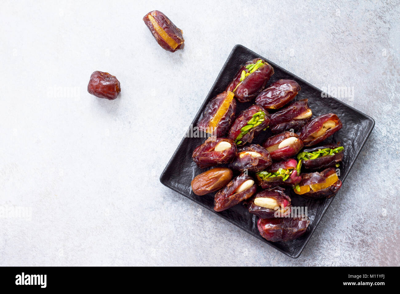 Stuffed dates with nuts and candied fruit filling on a stone or slate ...