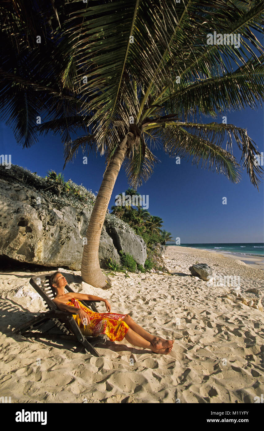 Mexico. Yucatan Peninsula. Tulum. Woman in deck chair sunning at beach ...