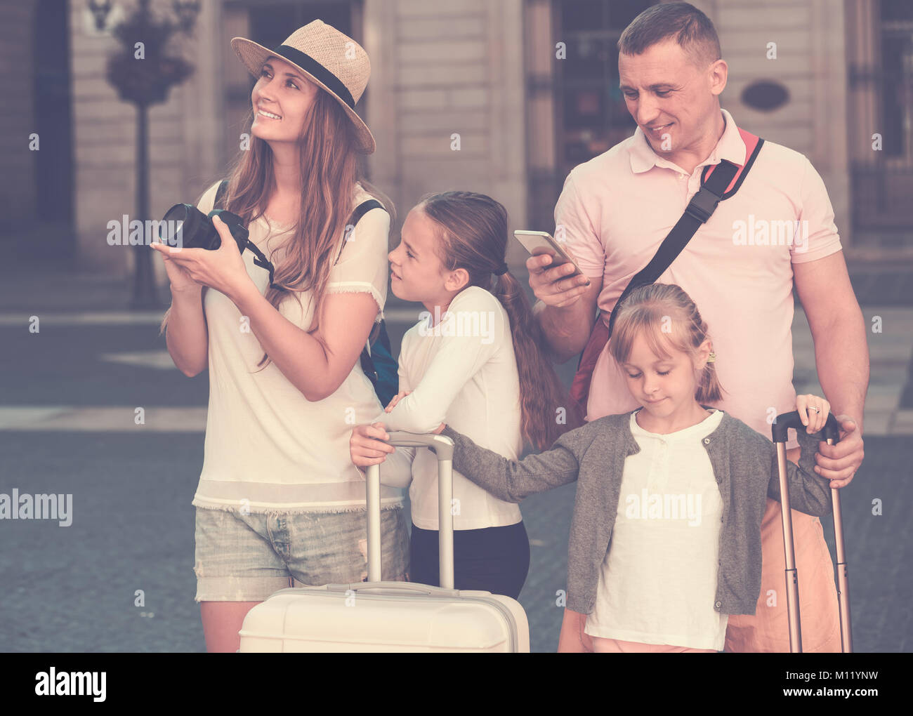 Smiling family with two kids using smartphone and photographing sights ...
