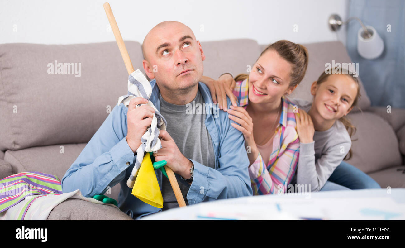 Tired father sitting near the table with mop after cleaning home Stock ...