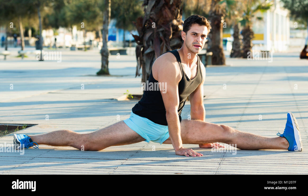 Muscular positive man during outdoor workout sitting on splits Stock ...