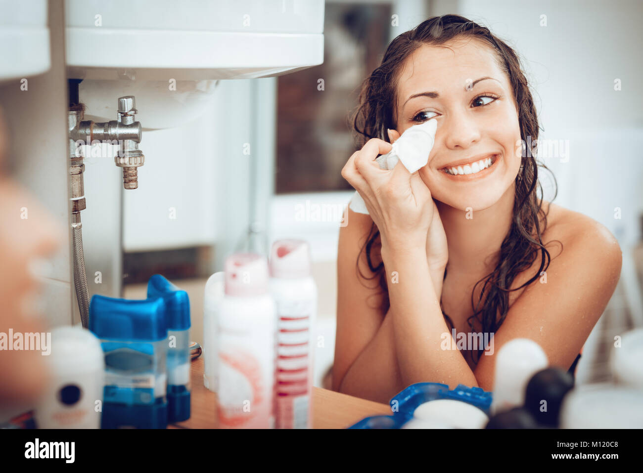 Beautiful smiling young woman removing make up in front of mirror Stock ...