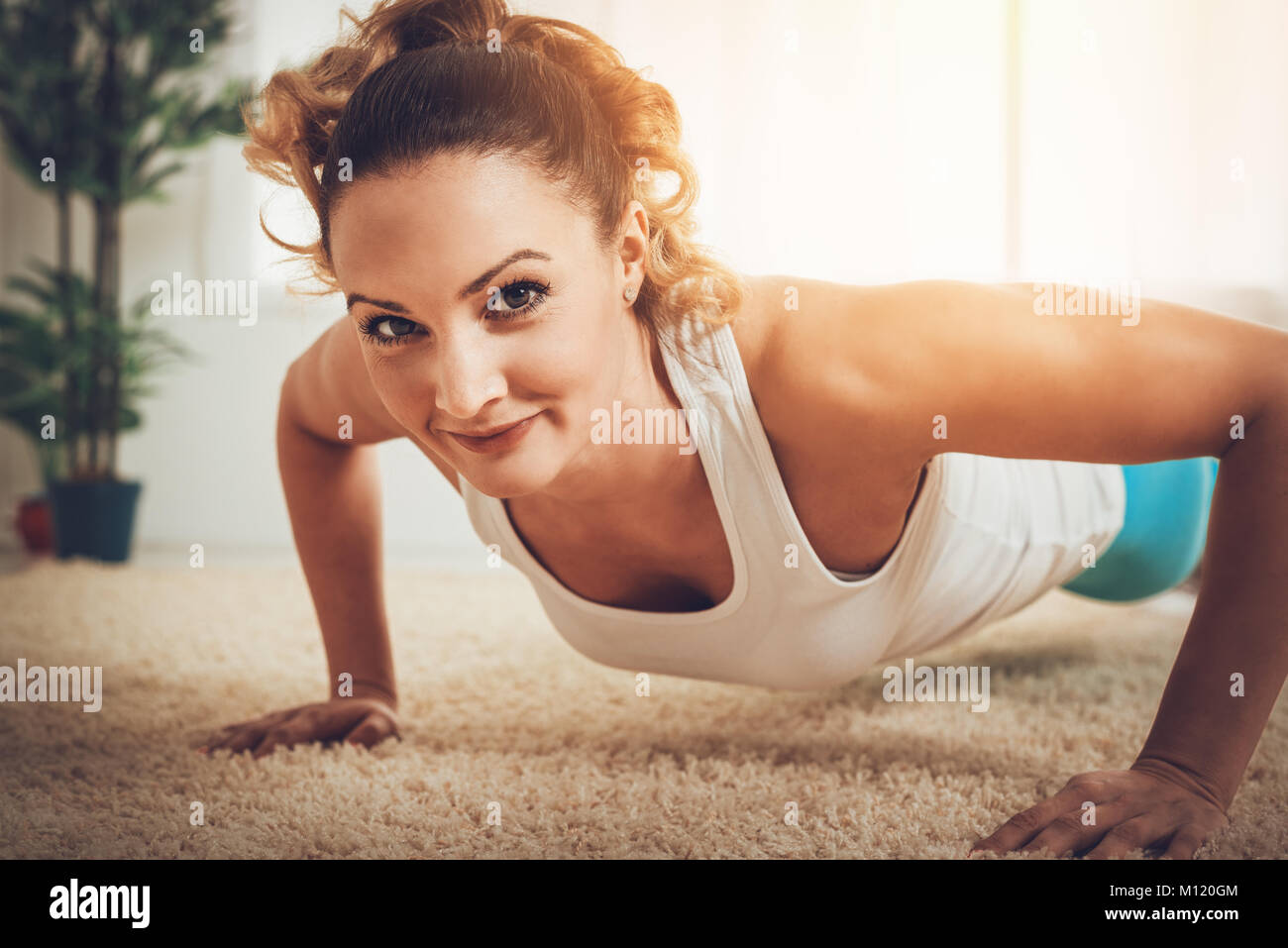 Beautiful muscular smiling girl doing push-up at flat. Looking at ...