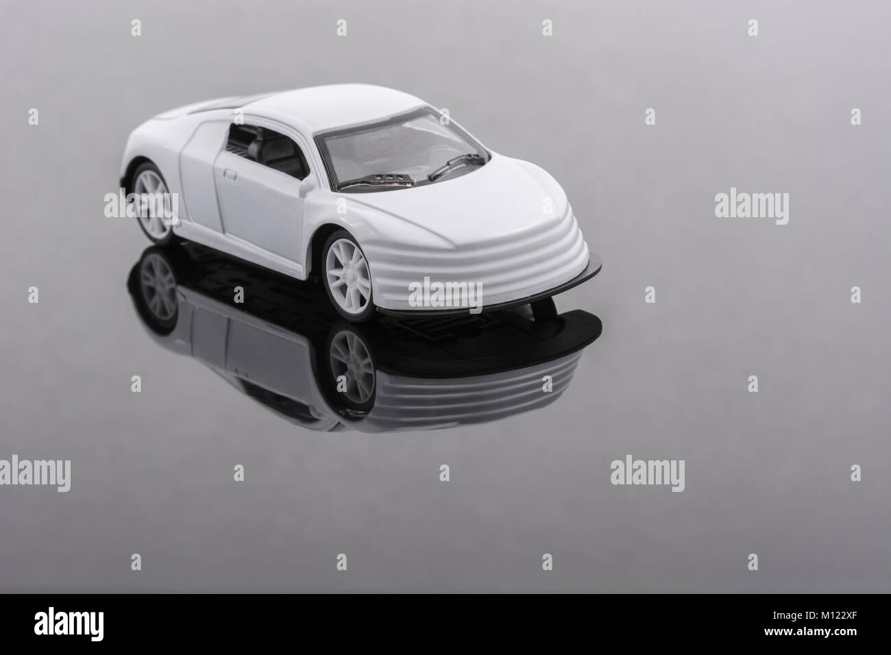 Small toy sports car / car toy on reflective surface - metaphor for ...