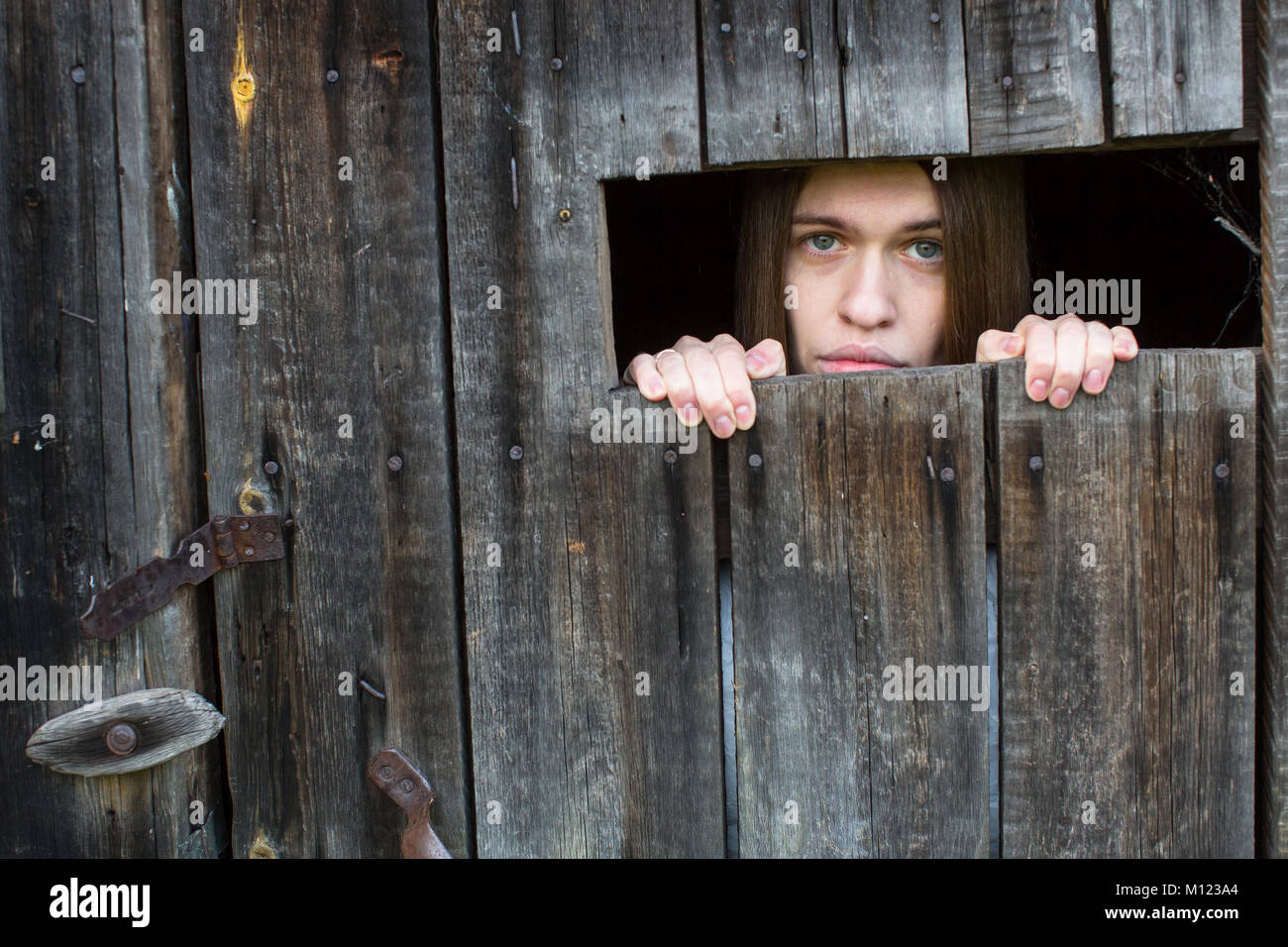 A young woman, locked in a wooden shed Stock Photo - Alamy
