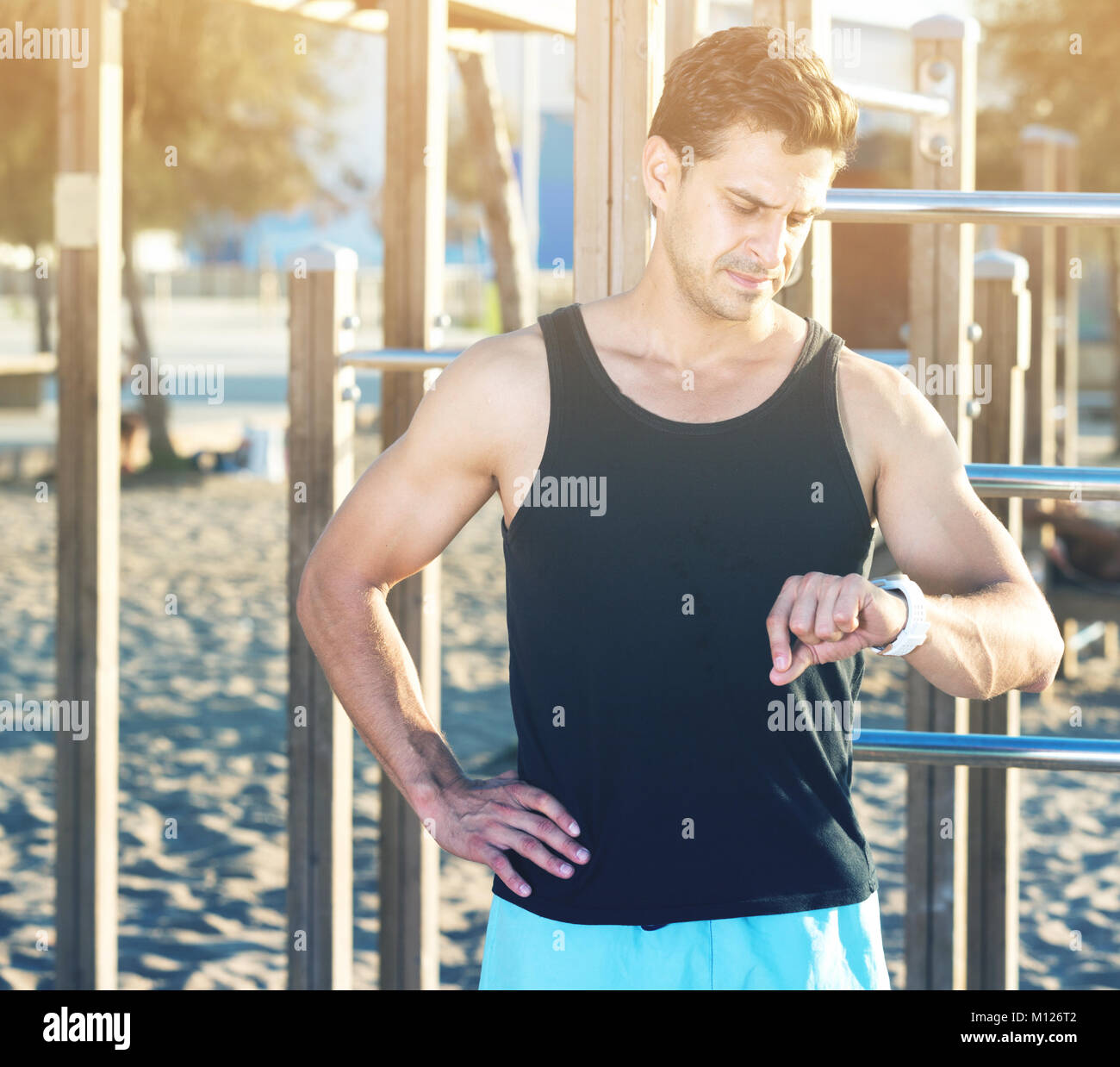 Physically fit man looking at smartwatch on sport ground on beach Stock ...