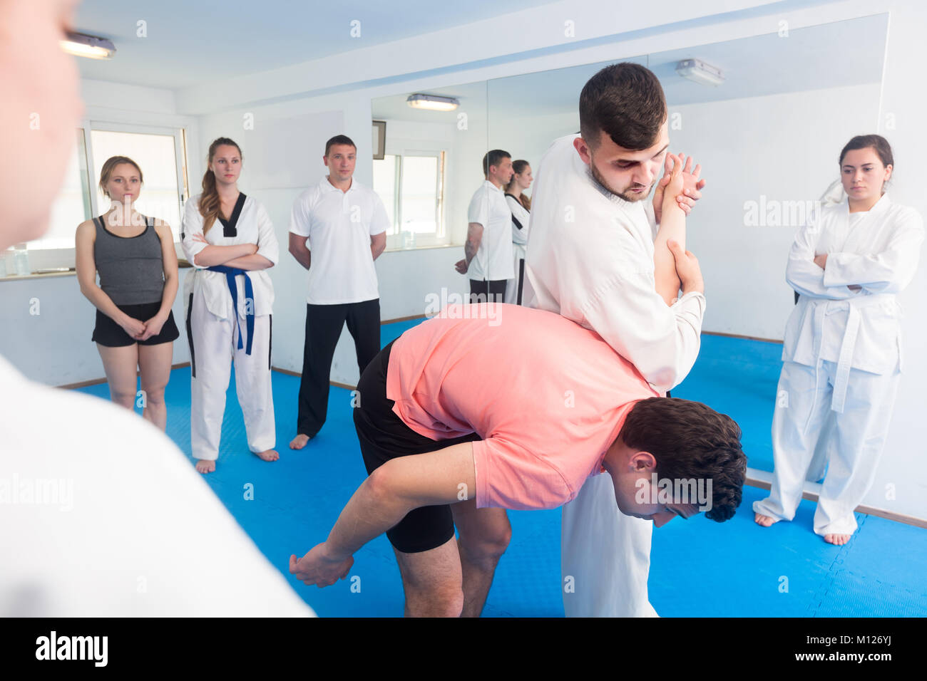 positive man training new taekwondo holds with adults during class ...