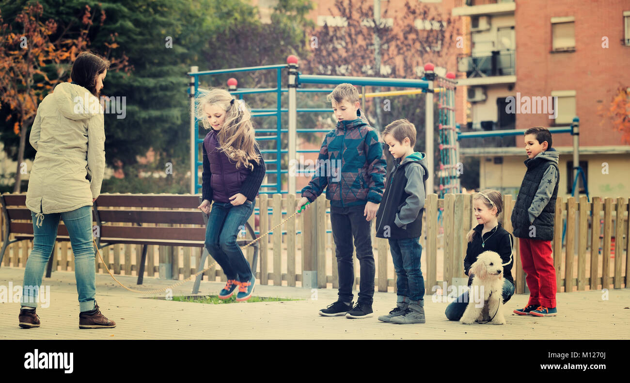 smiling children playing rubber band jumping game and laughing outdoors ...