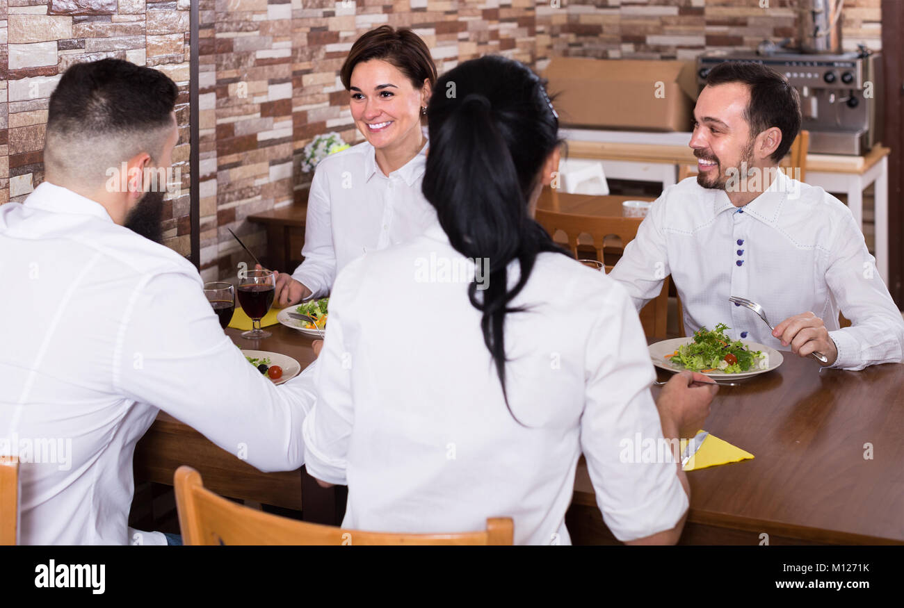 group of smiling friends eating at restaurant table and chatting Stock ...