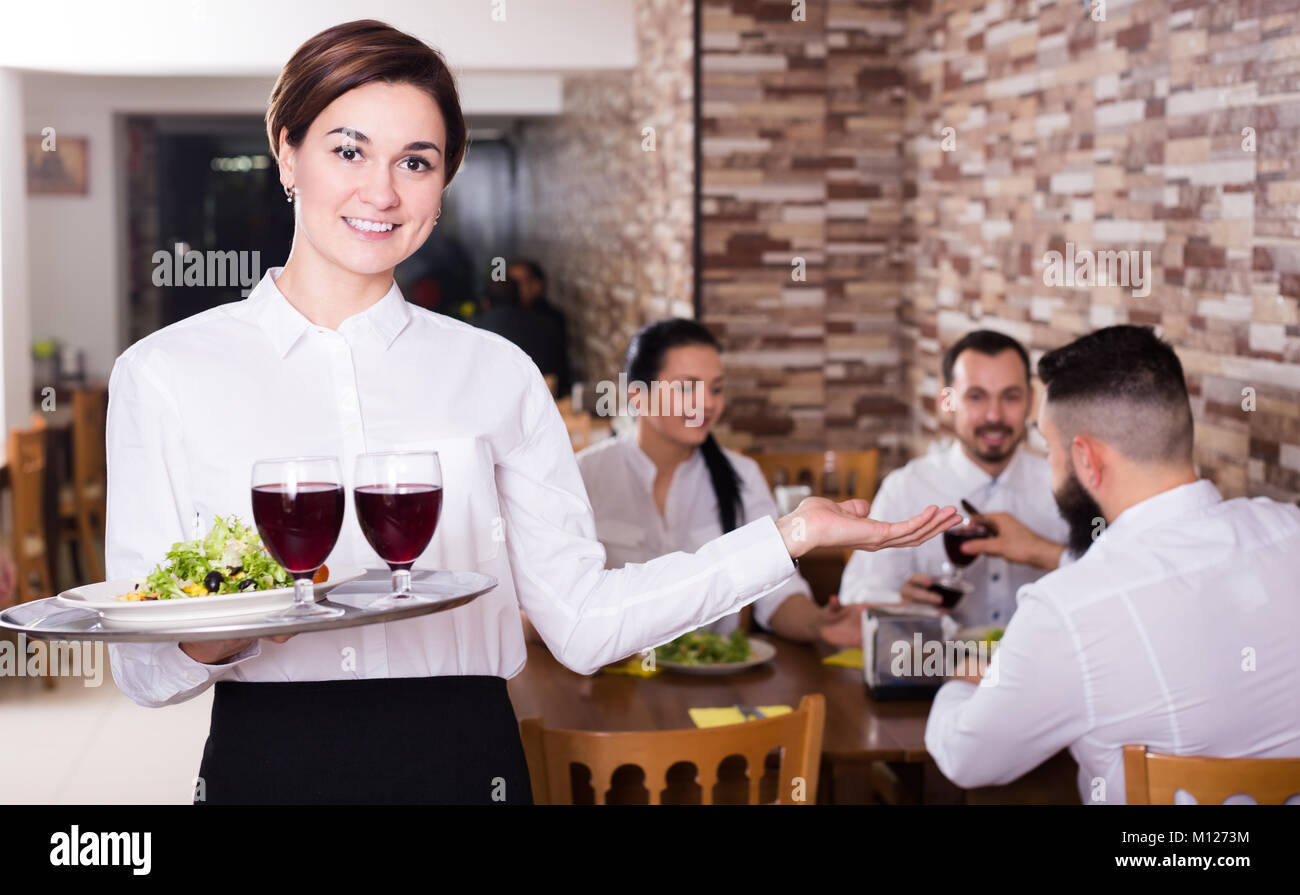 Portrait of waitress working in ordinary restaurant and holding tray ...