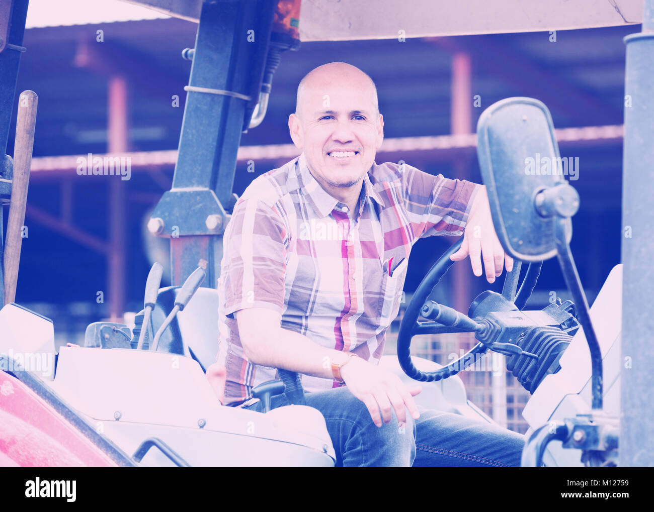 male driver operating modern tractor in livestock farm Stock Photo - Alamy