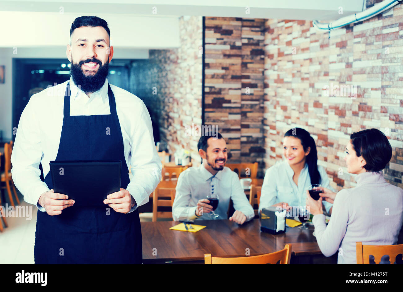 Positive waiter serving dear restaurant guests at table Stock Photo - Alamy