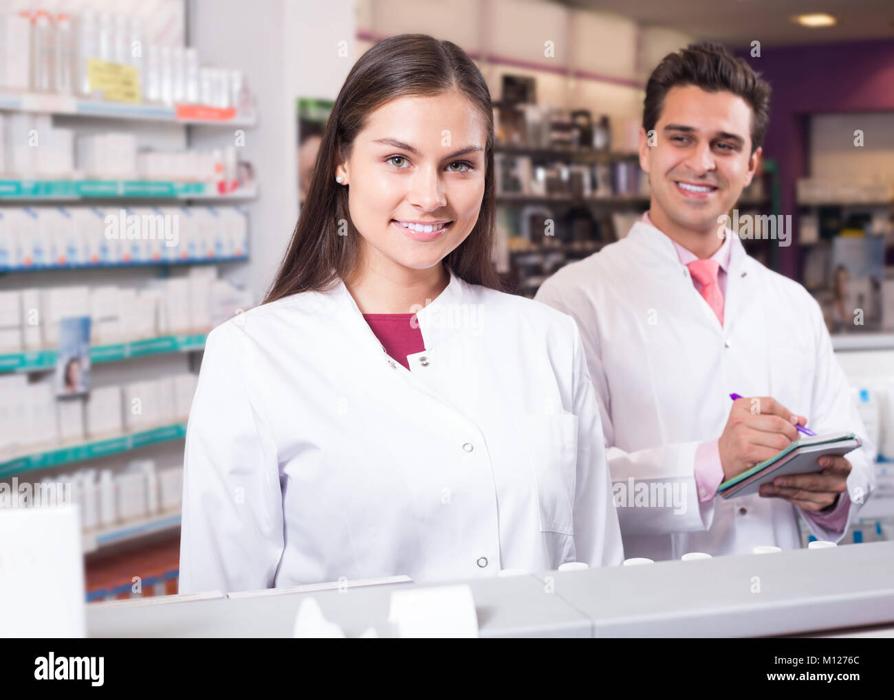 Professional smiling american pharmaceutists at reception of drugstore ...