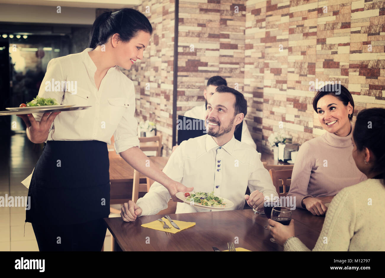 Young girl waitress serving meal for restaurant guests at table Stock ...
