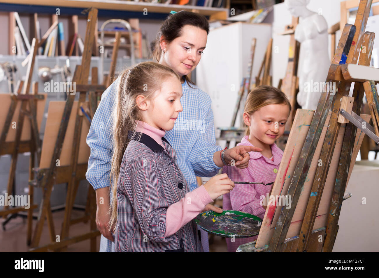 Smiling teacher giving workshop session during painting class at art ...