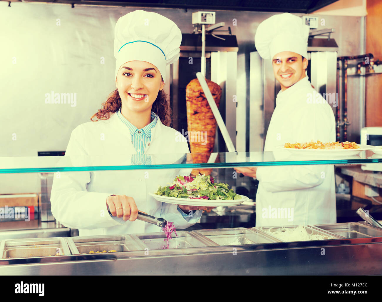 Pretty adult cafe staff posing at kebab counter and smiling Stock Photo ...