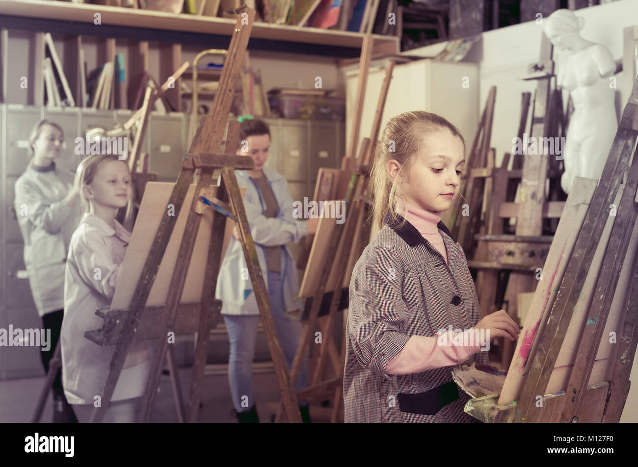 positive schoolgirls diligently training their painting skills during ...