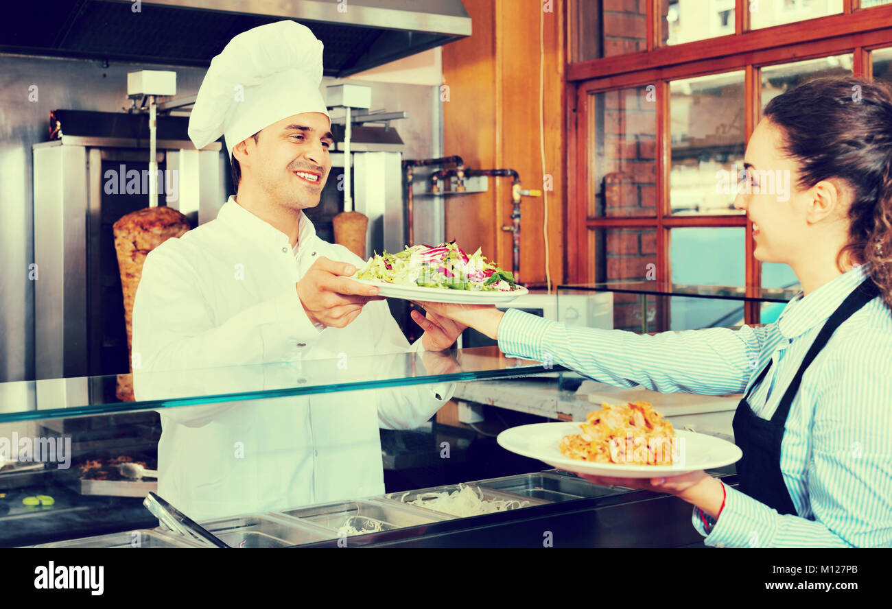 Happy positive smiling professional chef and young waitress taking ...