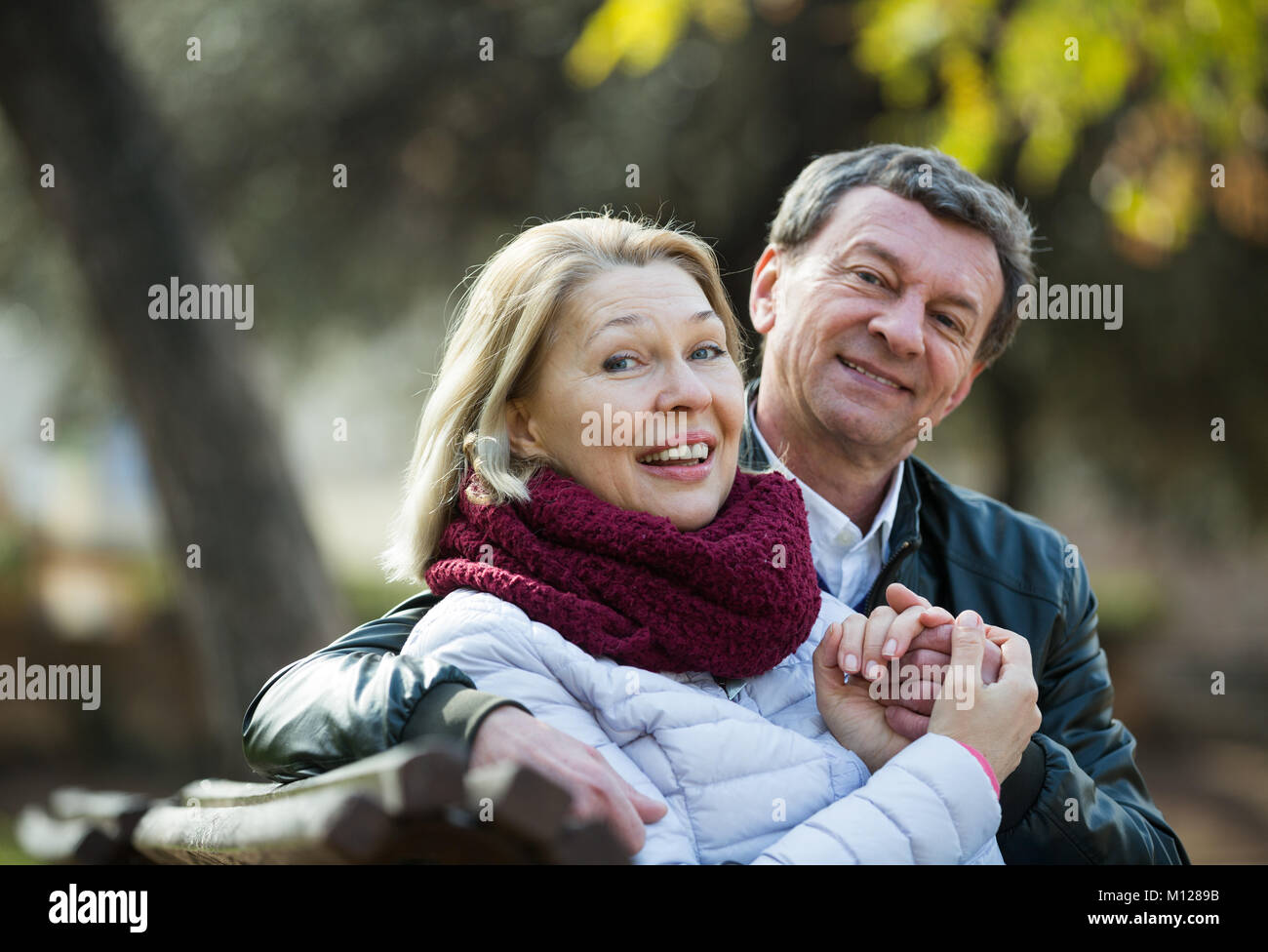 Portrait of senior couple cuddling in park and laughing Stock Photo - Alamy