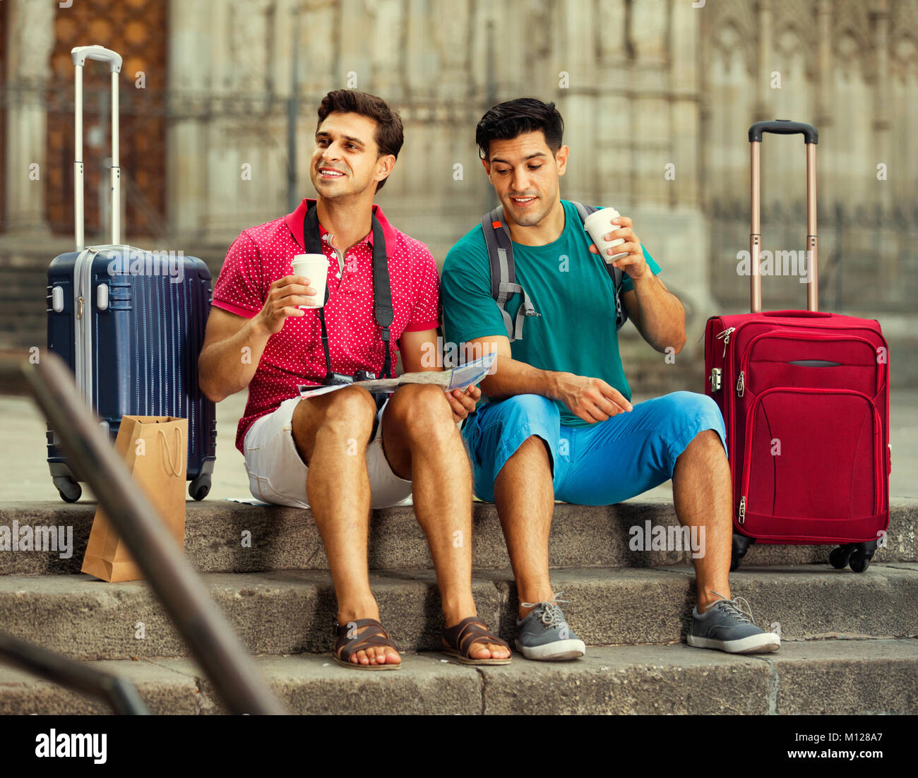 Happy cheerful smiling men tourists are sitting with coffee and ...