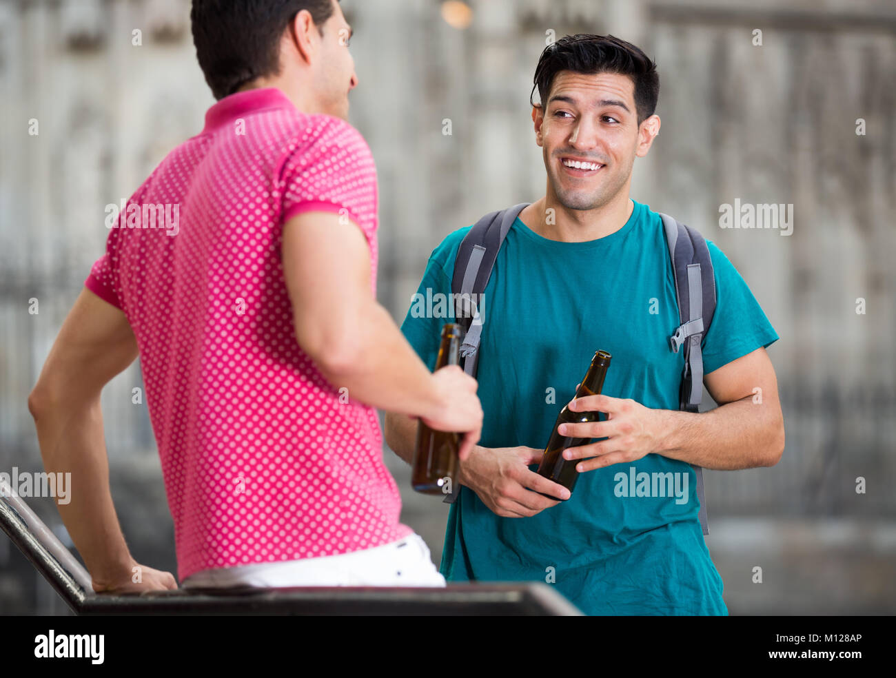 Men friends are talking and drinking beer in time walking in the city ...