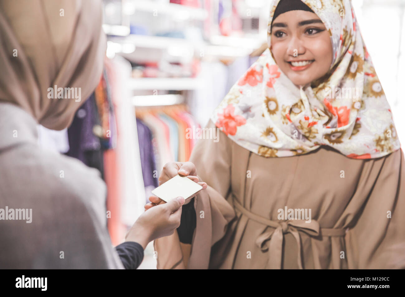 asian muslim woman paying with credit card in a fashion boutique Stock ...