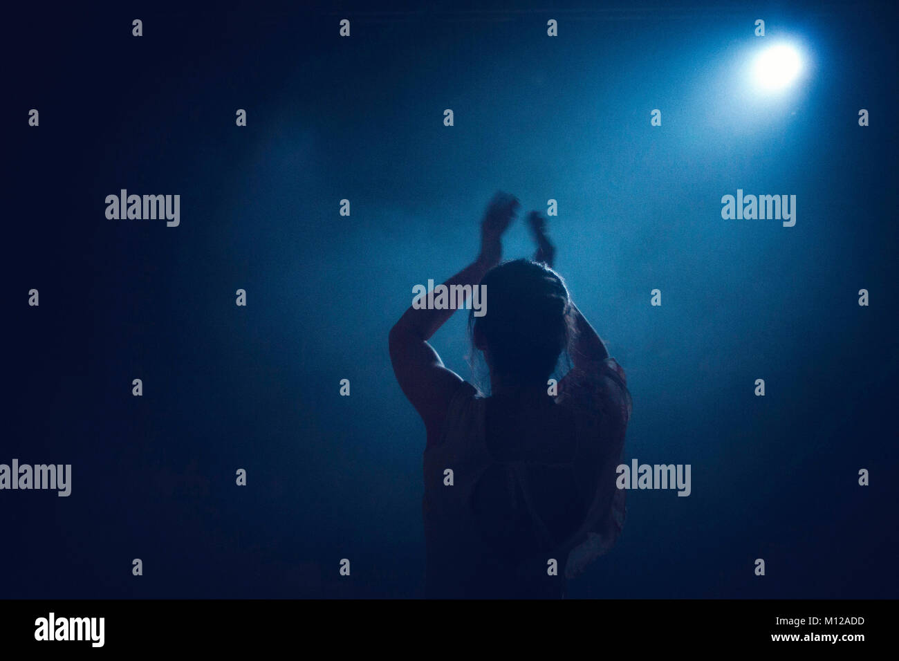 A woman is clapping her hands to the beat at the dance floor of a night ...