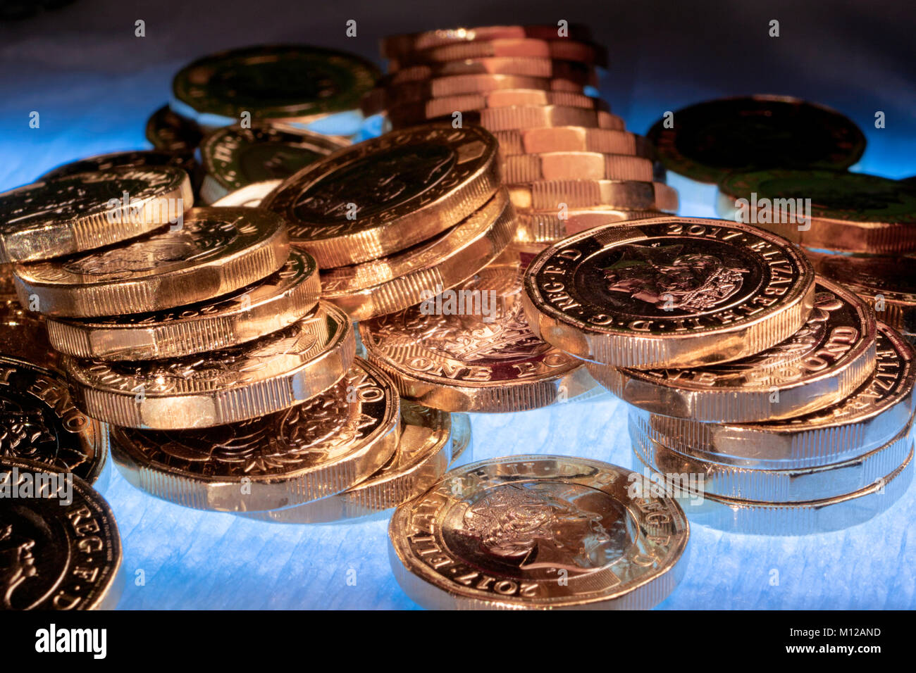 New UK One Pound coins, loosely arranged, and top lit on a blue ...