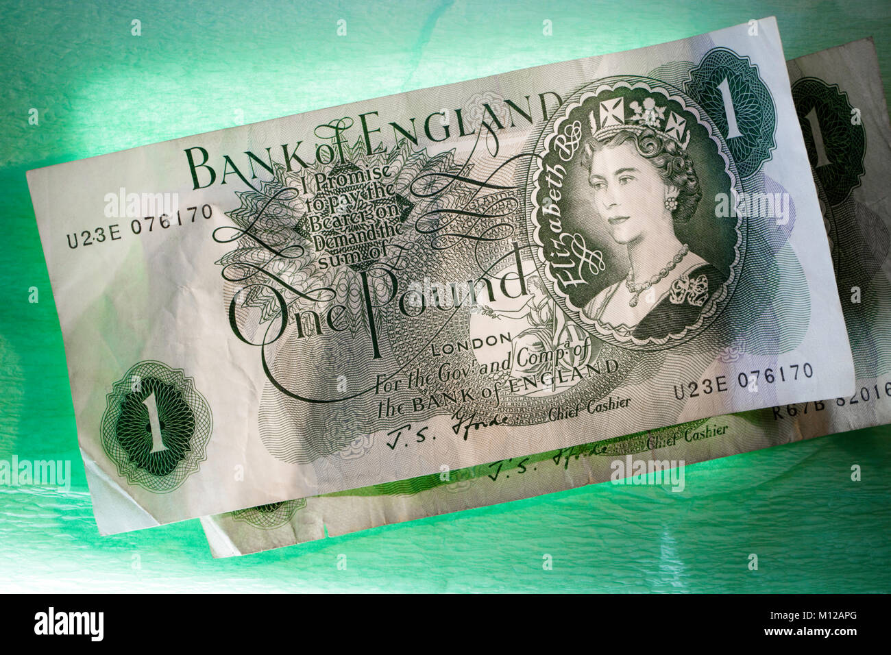 British One Pound notes, displayed on a green illuminated background ...