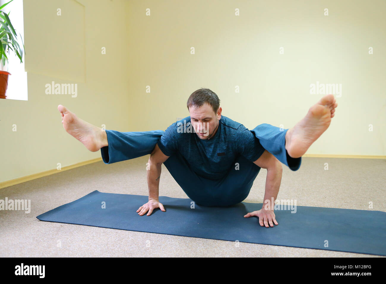 Man of European appearance sits on floor and performs cross twin Stock ...