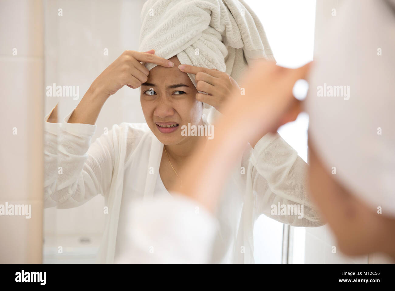 A portrait of an asian woman pressing acne on her forehead Stock Photo ...