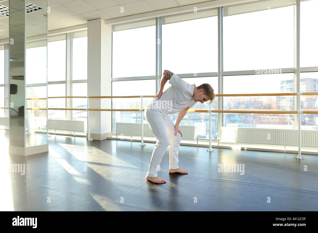Young person making leg stretching near window Stock Photo - Alamy