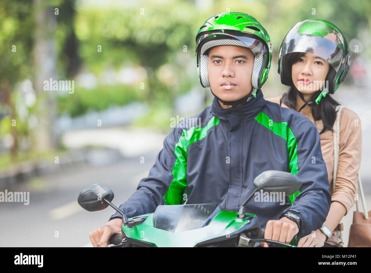 professional motorcycle taxi driver taking a passenger to her ...