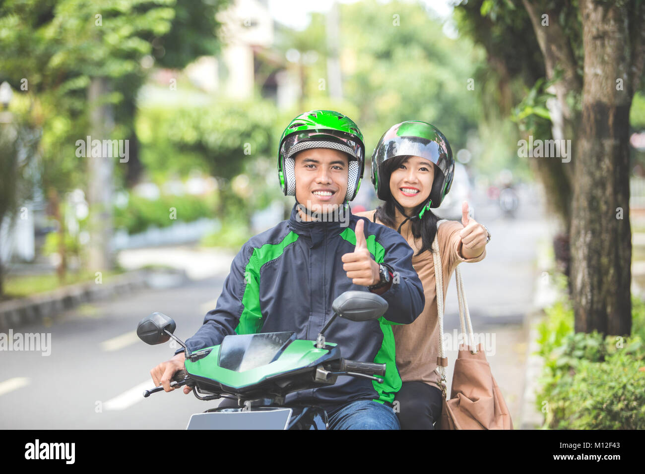 Happy commercial motorcycle taxi driver and his passenger showing thumb ...