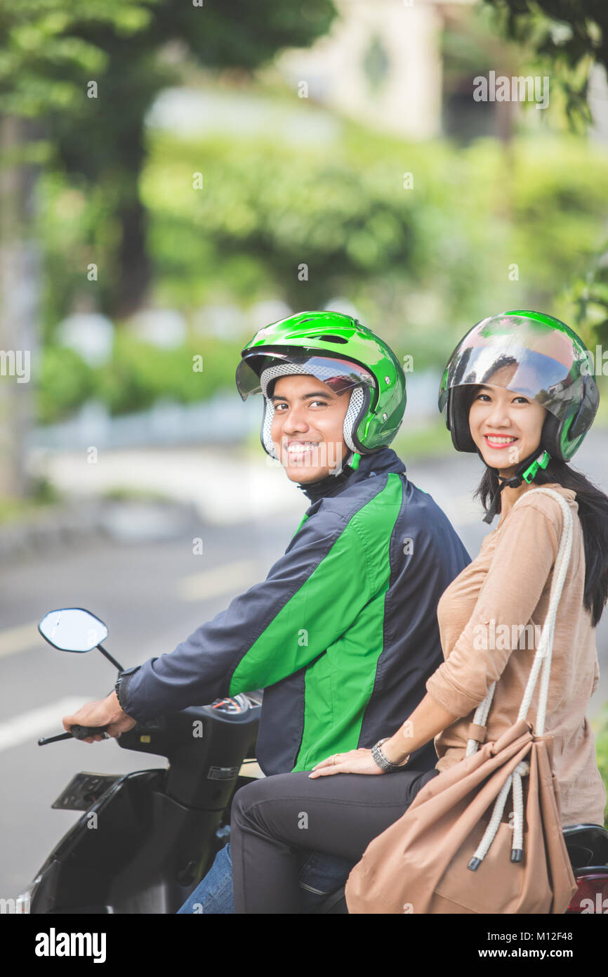 Happy commercial motorcycle taxi driver taking his passenger to her ...