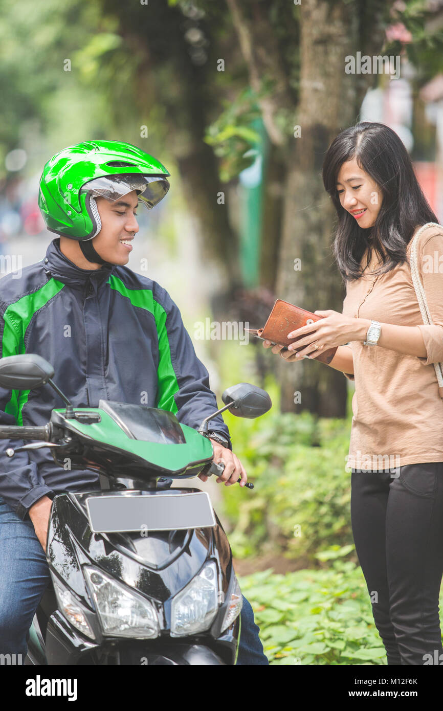 portrait of happy customer pay for her ride to motorcycle taxi driver ...