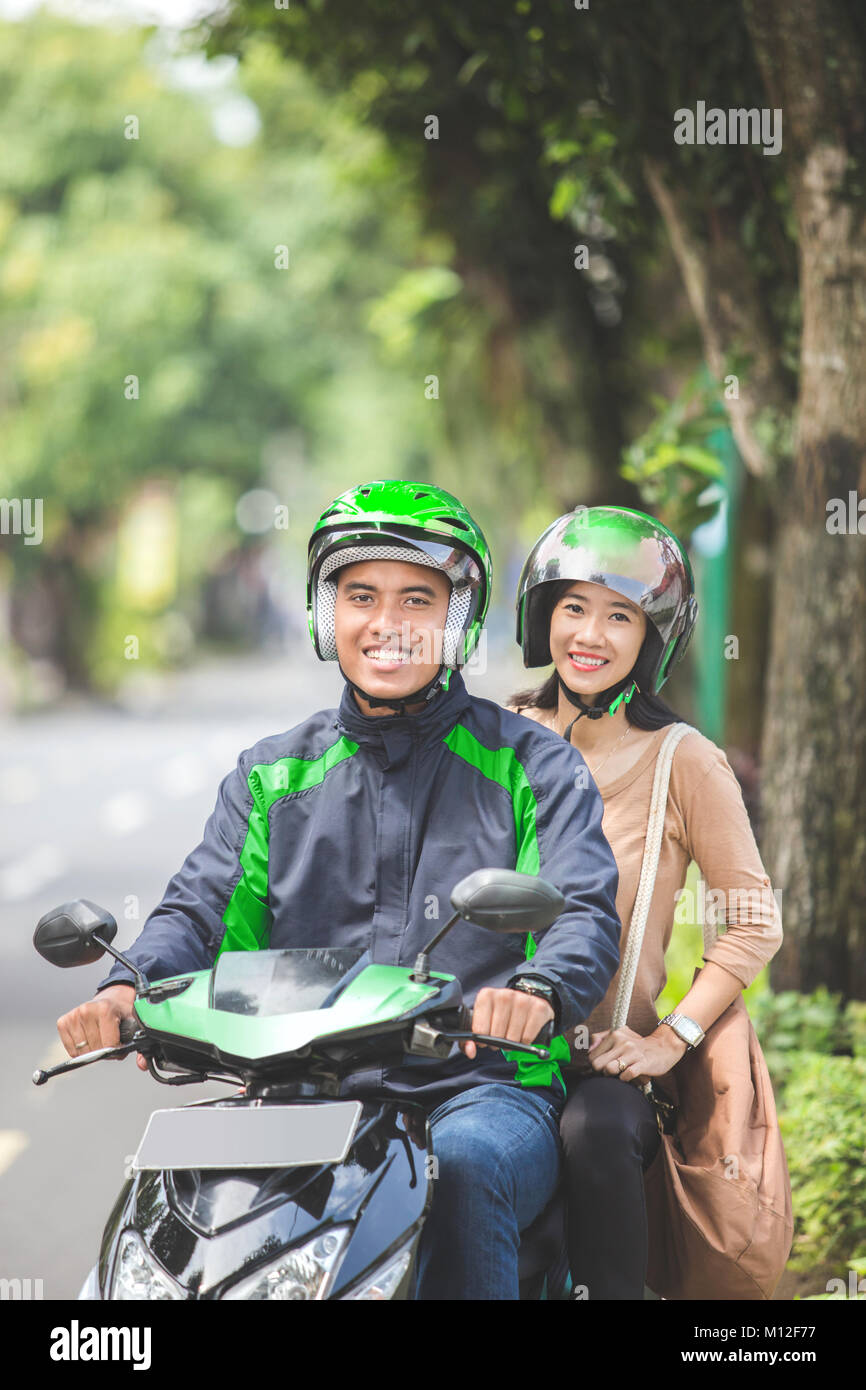 Happy commercial motorcycle taxi driver taking his passenger to her ...