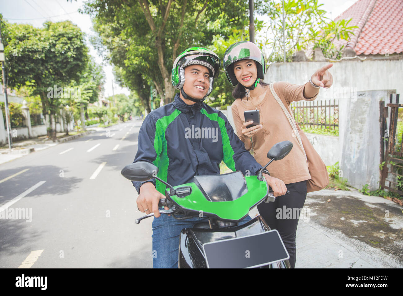 happy passenger directing commercial motorcycle taxi driver to go to ...