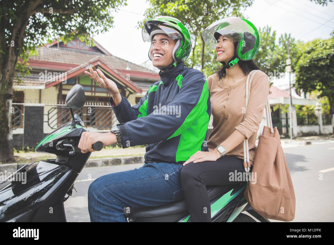 Happy commercial motorcycle taxi driver taking his passenger to her ...