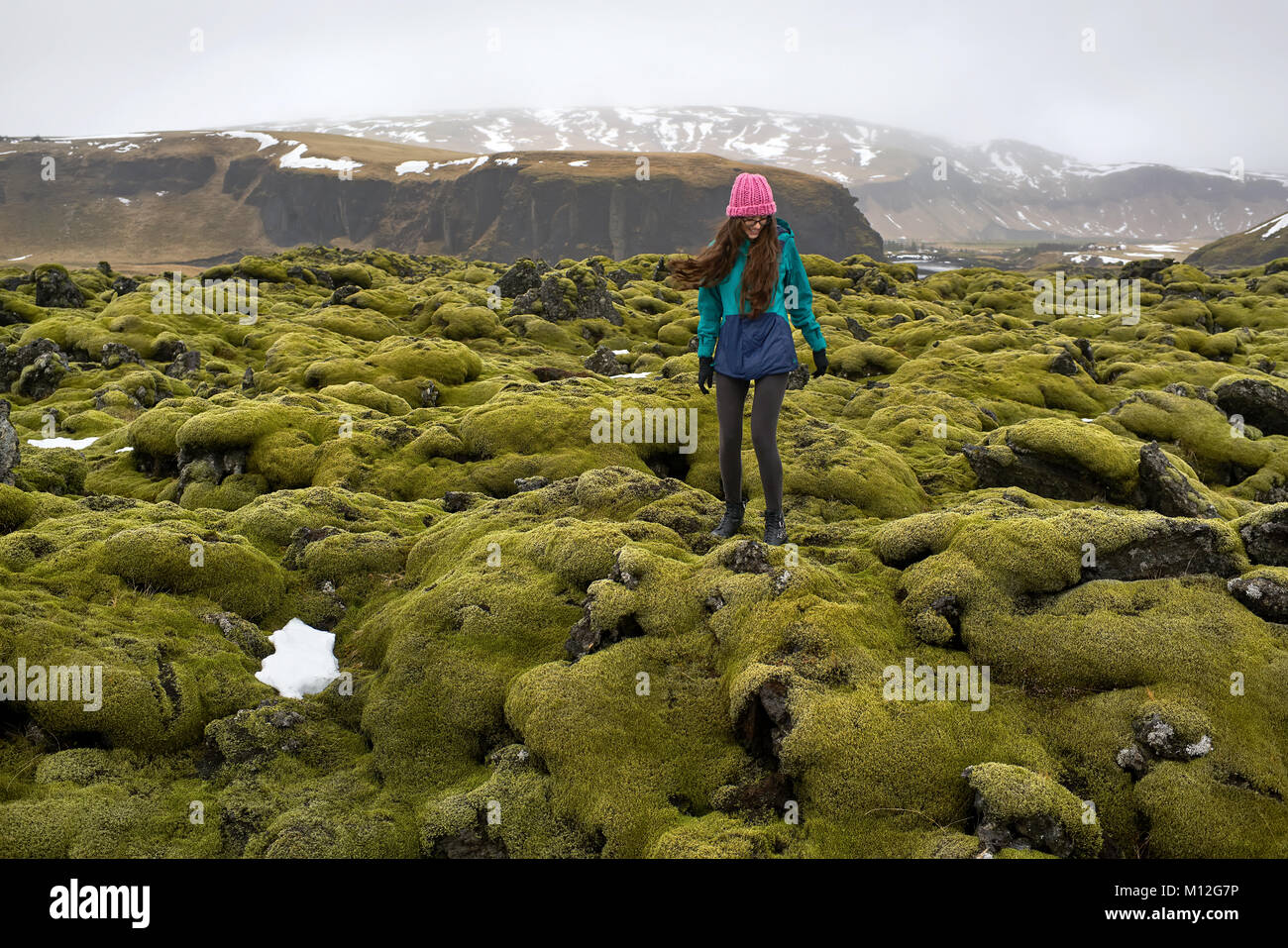 Happy girl in glasses stands on the green moss field with remains of ...