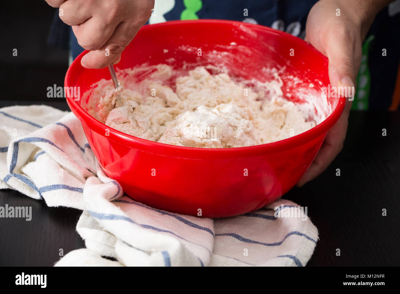 Male hands making/ mixing dough in red bowl, baking preparation closeup ...