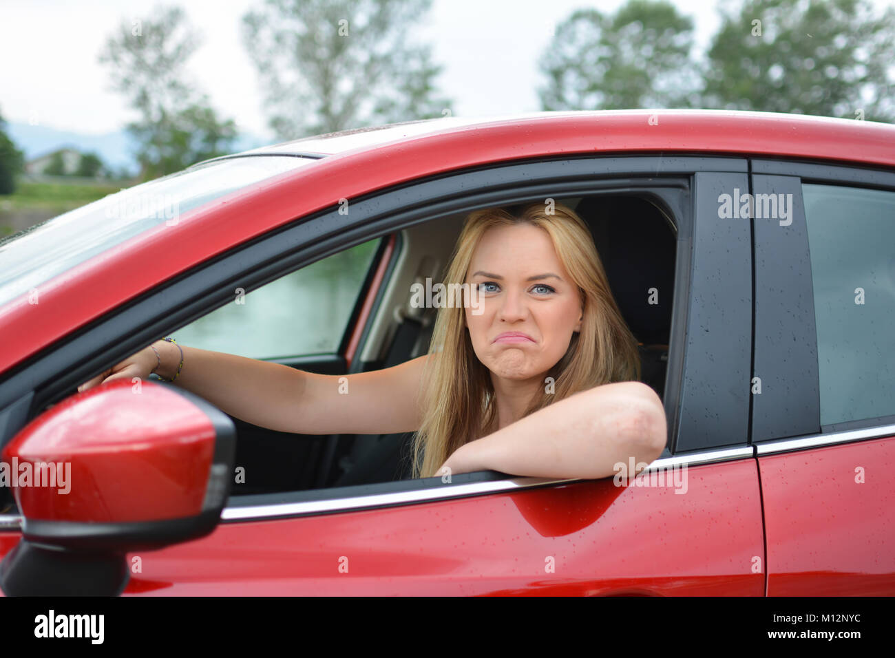 Young, attractive blonde girl in new red car, with strange facial ...